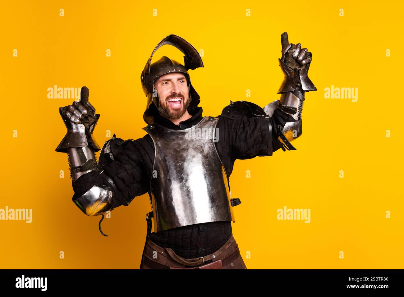 Cheerful knight in full armor suit expressing joy on yellow background ...