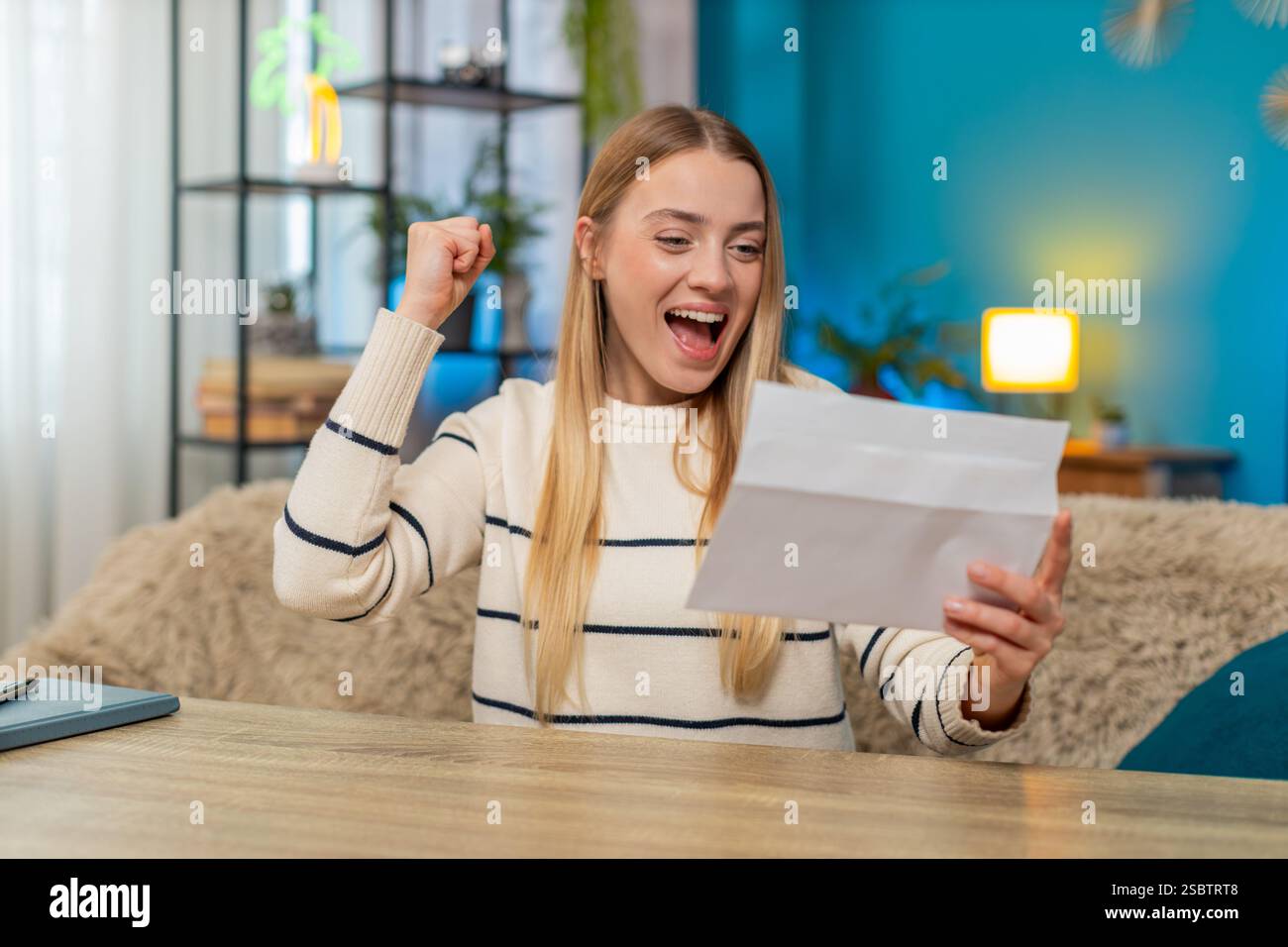 Caucasian woman sits at home opening an envelope, reading important ...