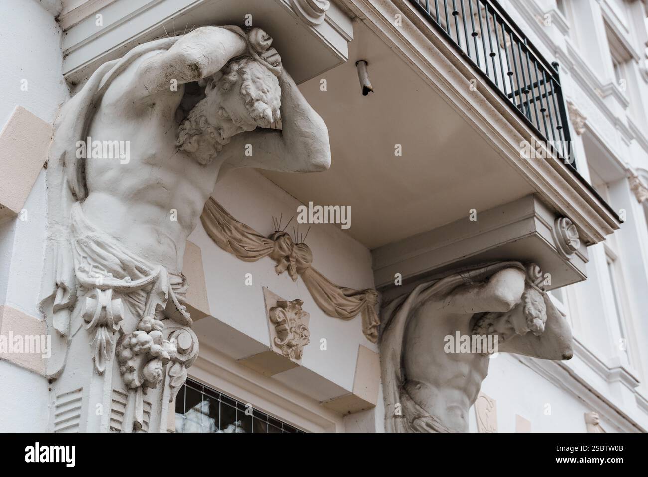 Two stone male sculptures with muscular bodies hold up a balcony on the ...