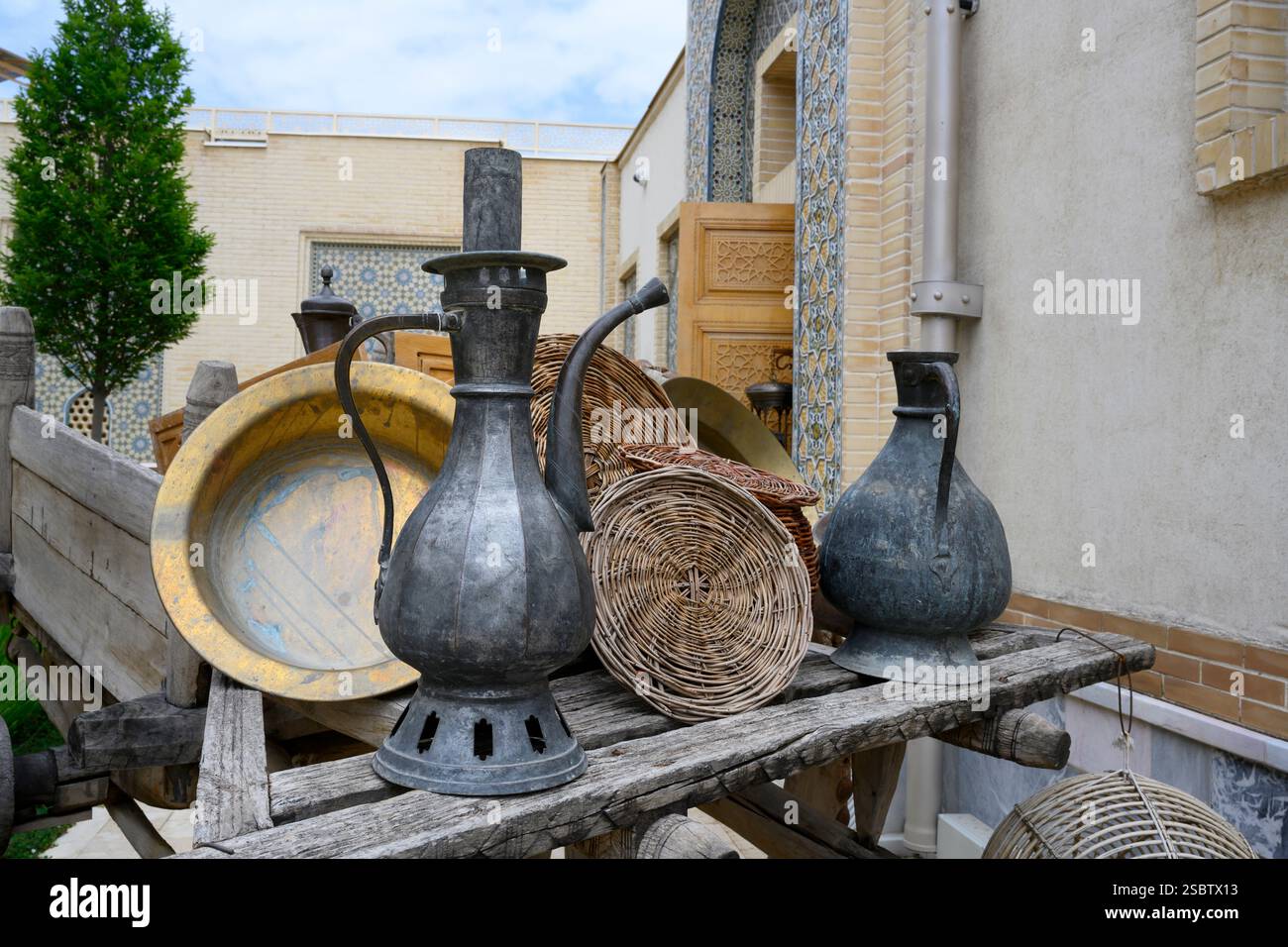Traditional Uzbek metal jug, plates and wicker baskets in an old wooden ...