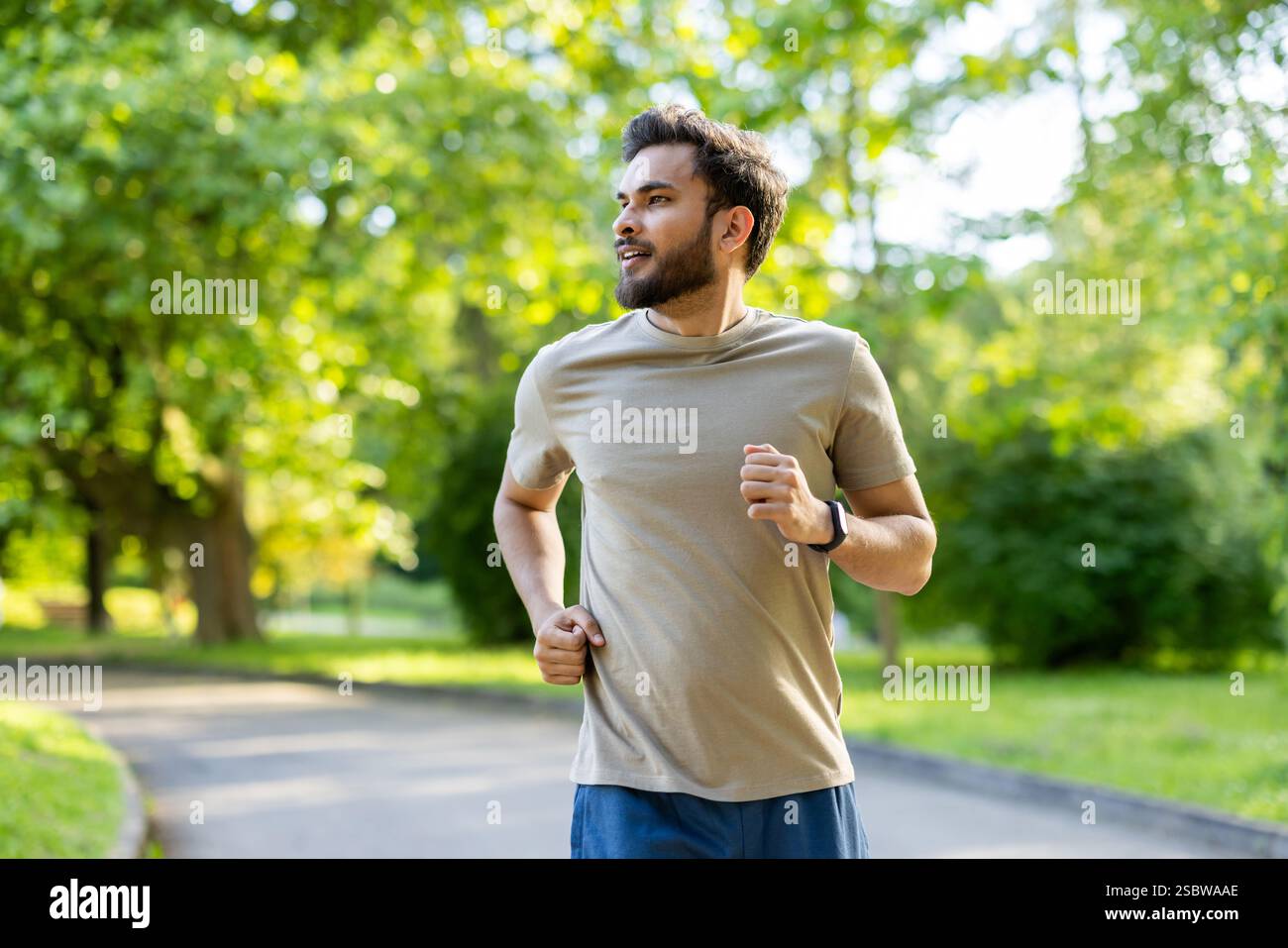 Man running in park surrounded by lush greenery showing joy and ...