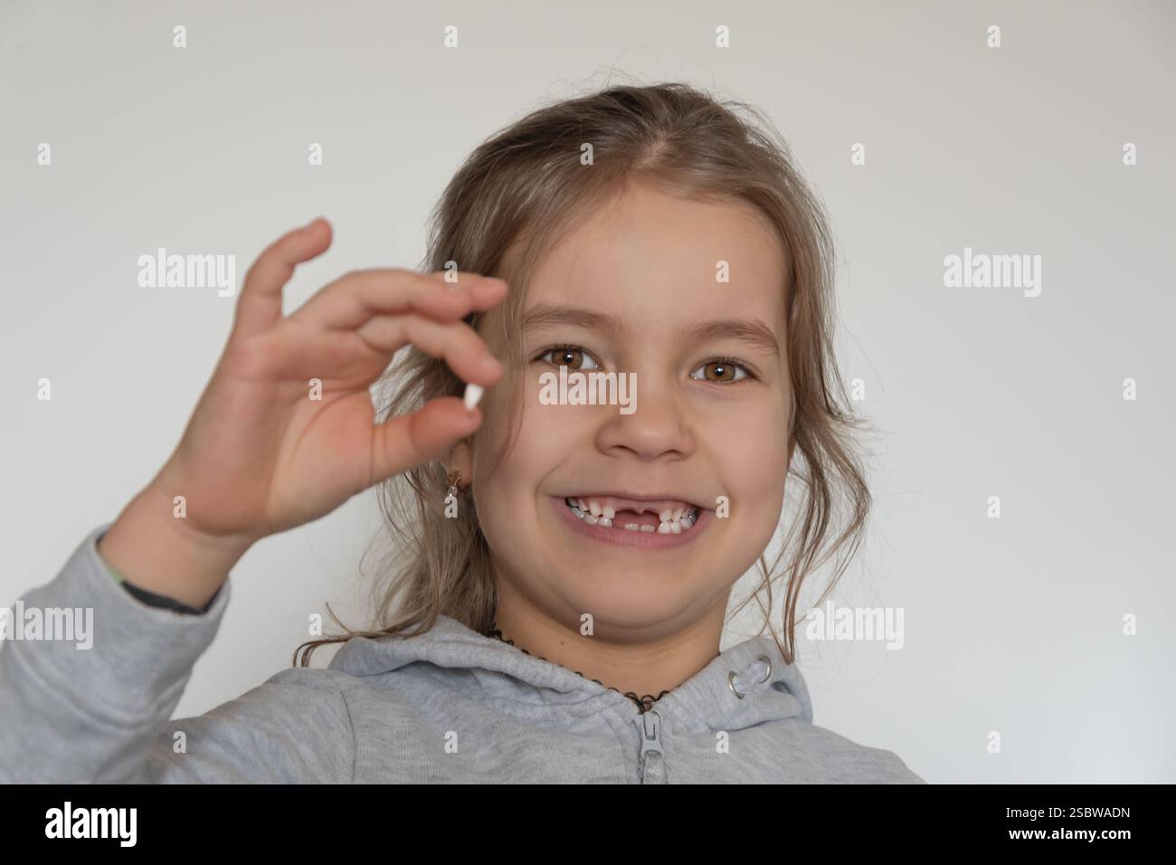 A child with a loose tooth holds it in his hand, showing a happy smile ...