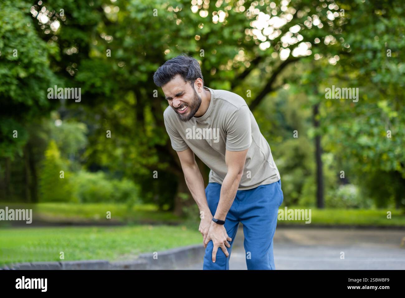 Man feeling knee pain during fitness exercises in nature setting ...