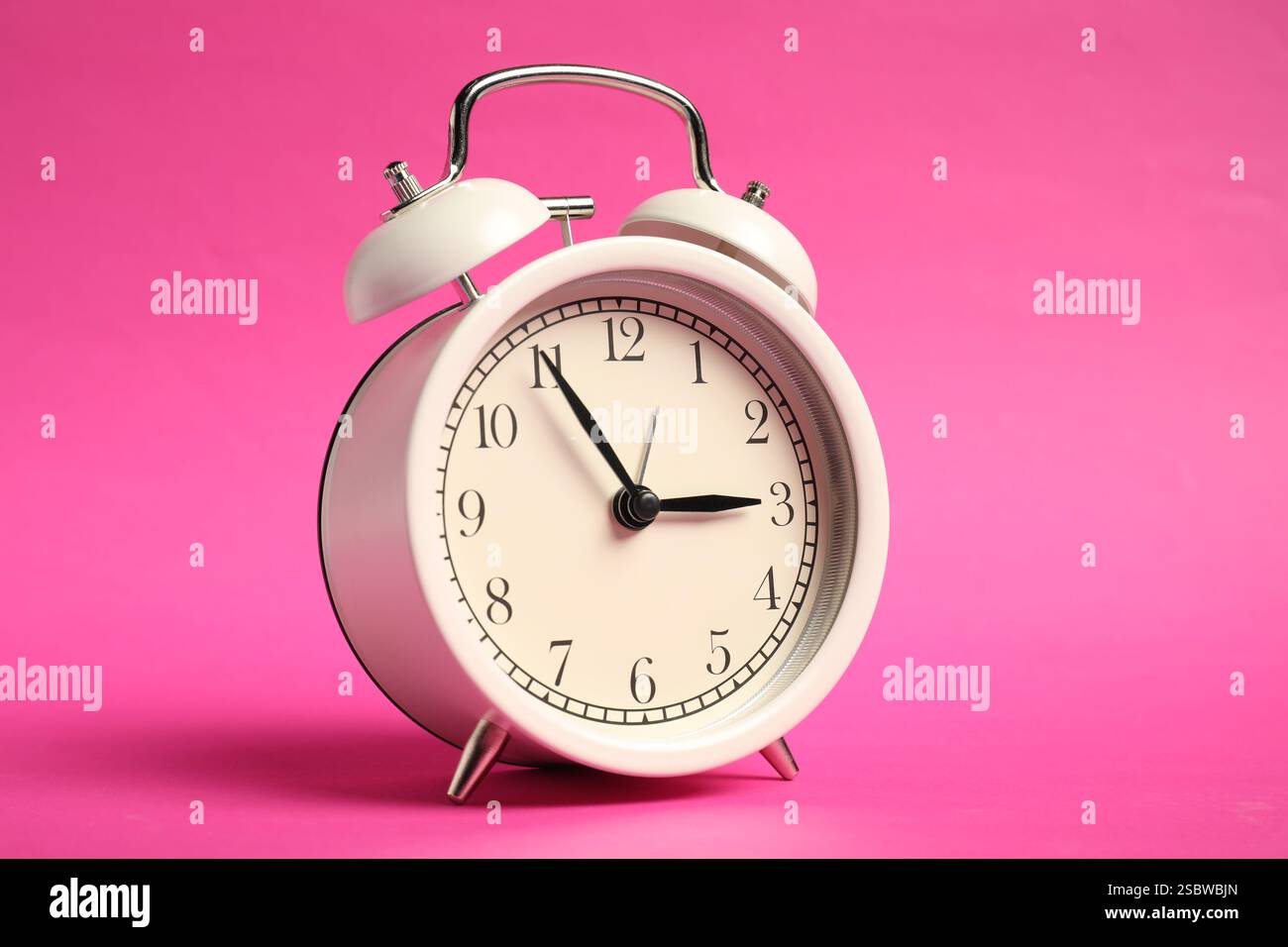 One white alarm clock on bright pink background Stock Photo - Alamy