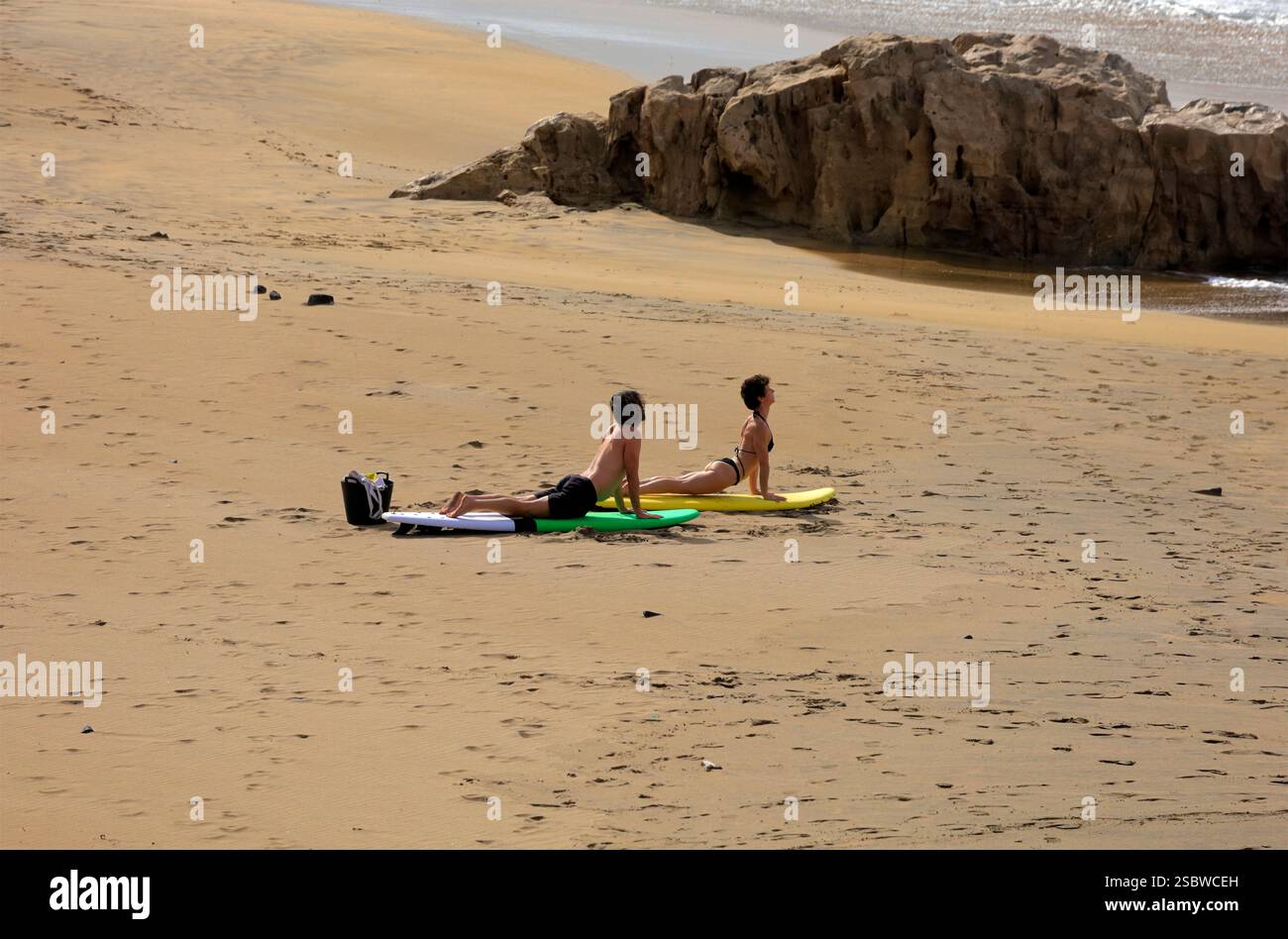 A man and woman practicing cobra yoga move on surf boards at Piedra ...