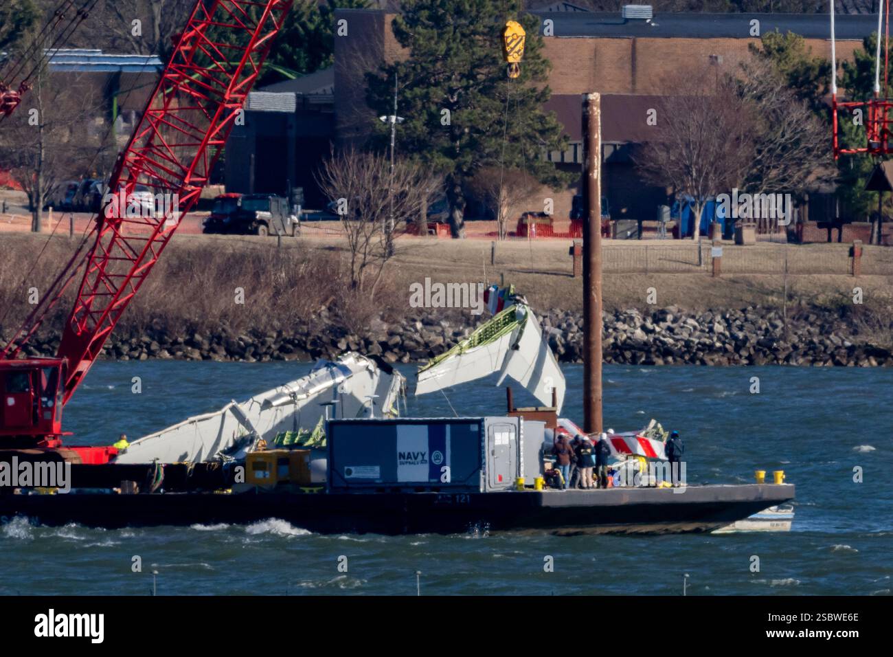 A piece of wreckage is lifted from the water onto a salvage vessel ...