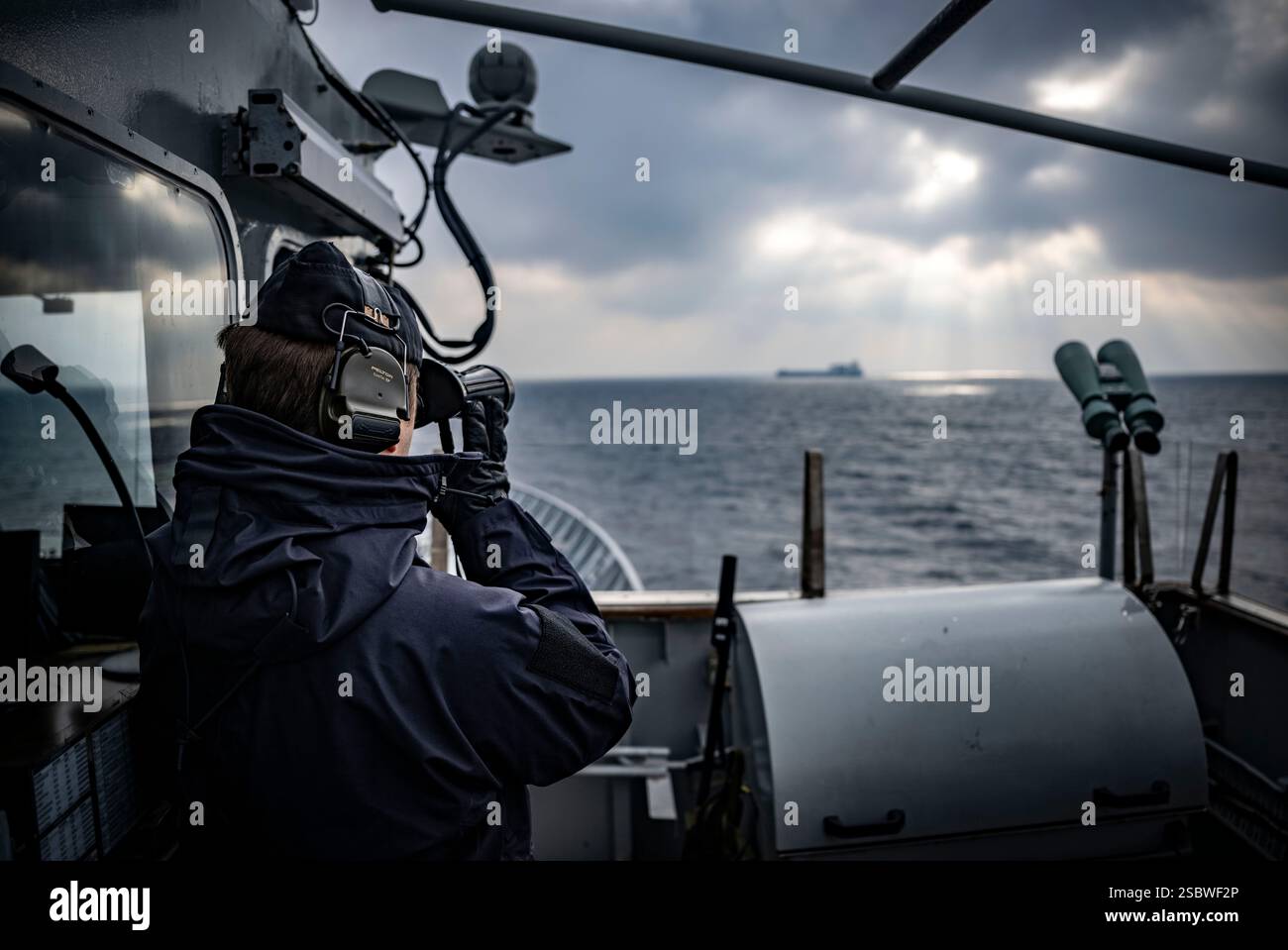 A cargo ship on the horizon is viewed through the lookout's binoculars ...