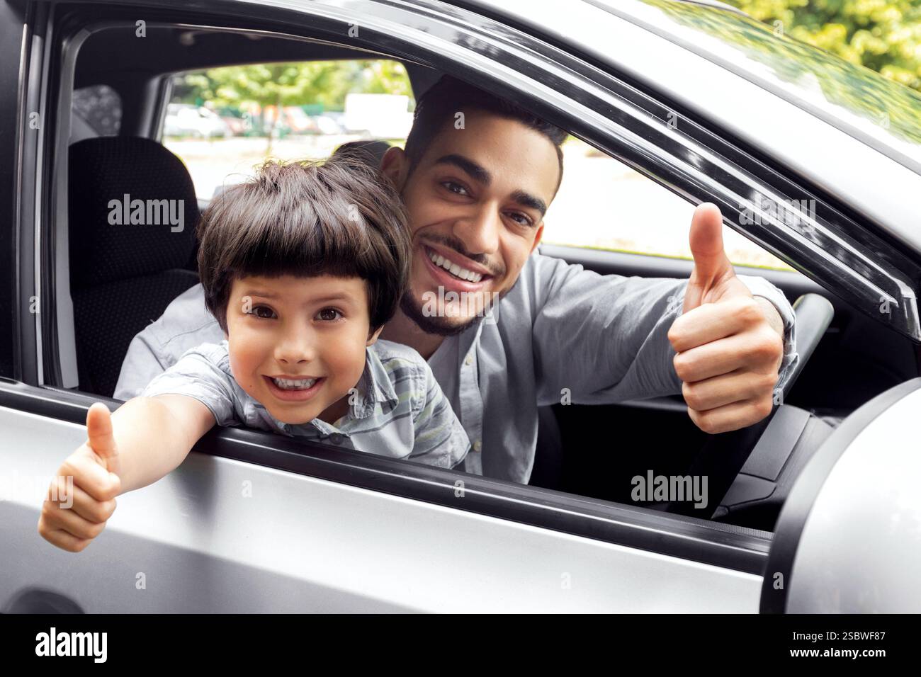 Glad happy millennial arab guy teaches little boy to drive car, dad and ...