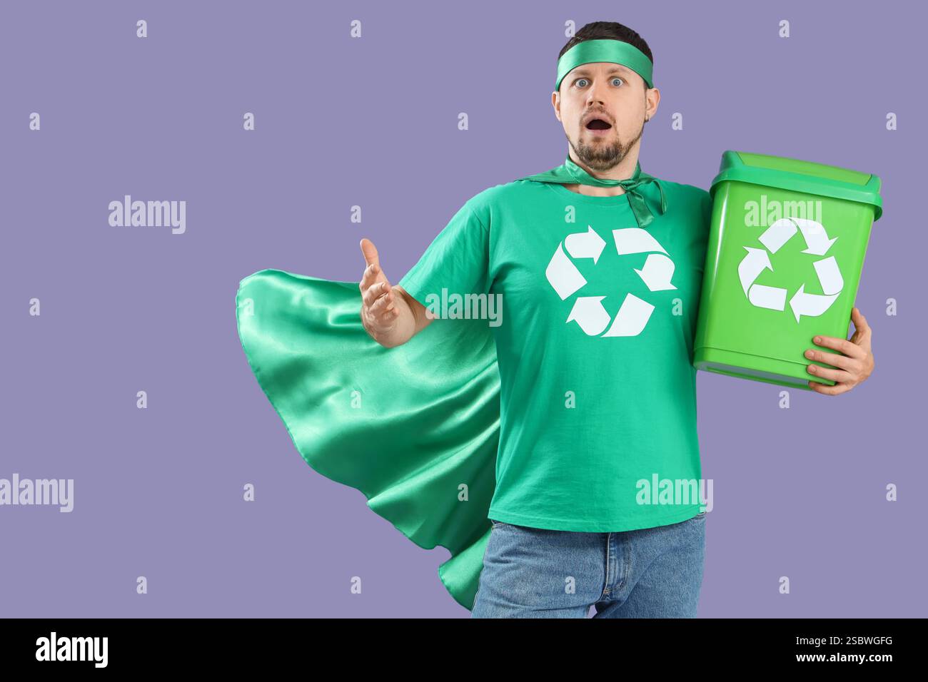 Confused young man dressed as eco superhero with garbage bin on lilac ...