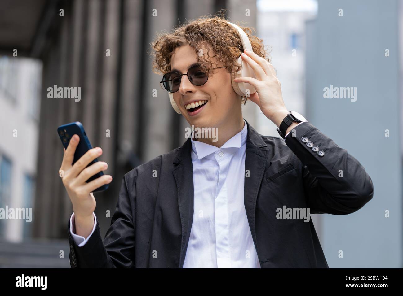Happy joyful Caucasian manager listens to music on wireless headphones ...
