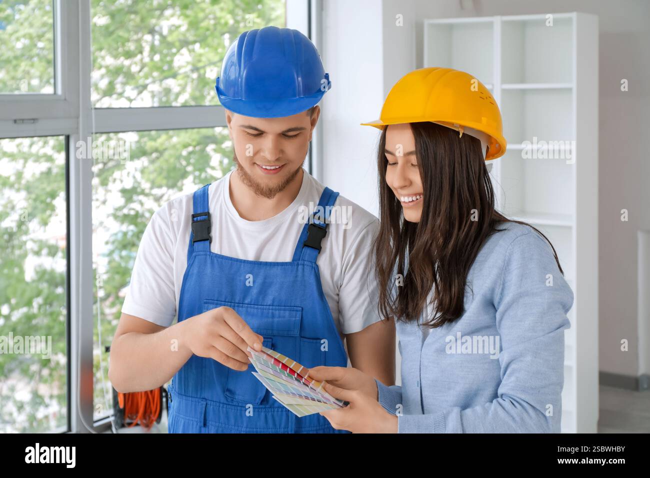 Male contractor and client with paint color palettes in room Stock ...