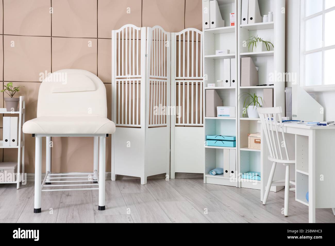 Interior of medical office with couch, doctor's workplace and folding ...