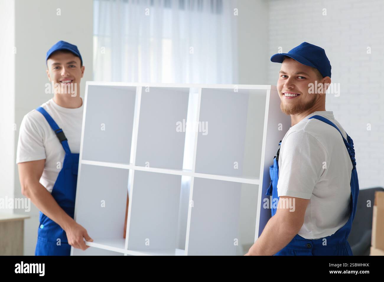 Loaders carrying shelving unit at home on moving day Stock Photo - Alamy