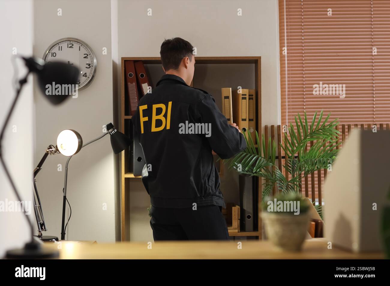 Male FBI agent taking folder from shelf in office, back view Stock ...