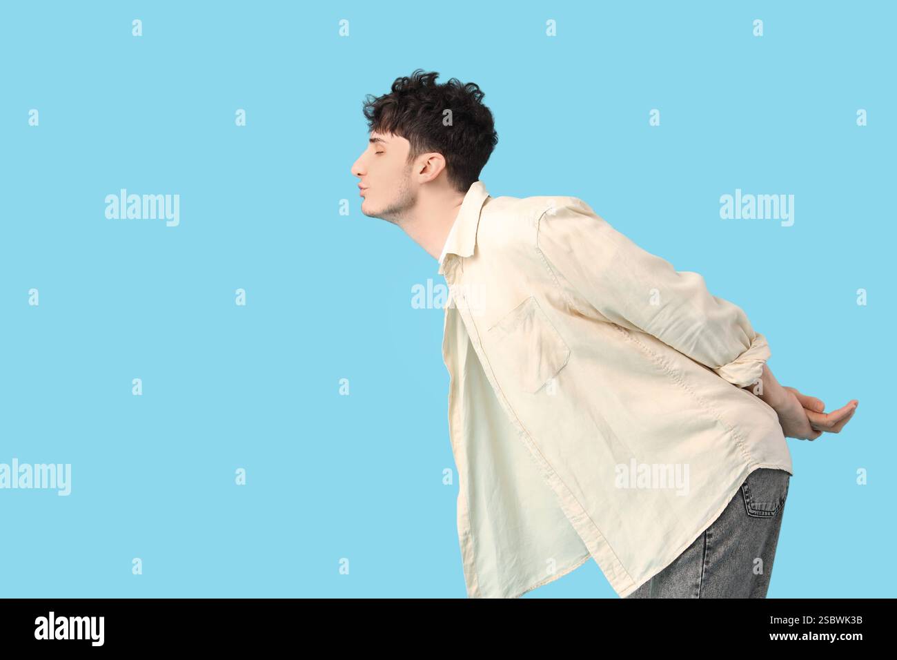 Handsome young man with puckered lips leaning for kiss on blue ...