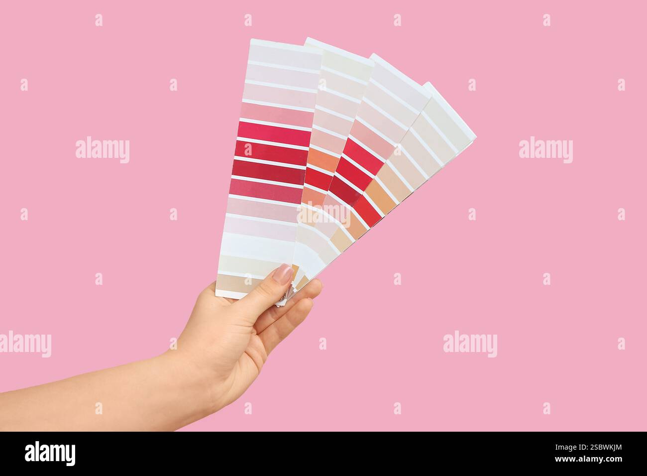Female hand with paint color palettes against pink background, closeup ...