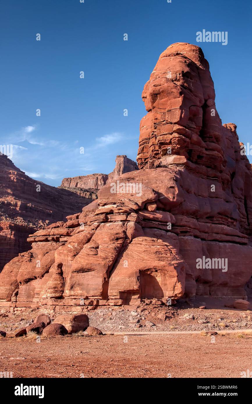 A large rock formation in the desert. The rock is brown and has a large ...