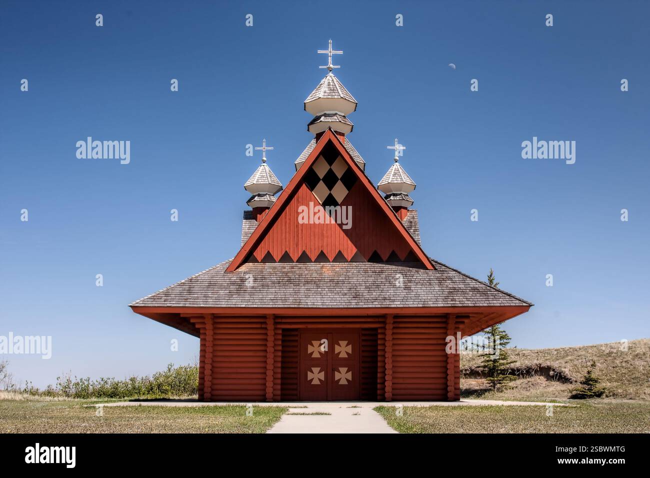 A red church with three crosses on top. The roof is made of wood. The ...
