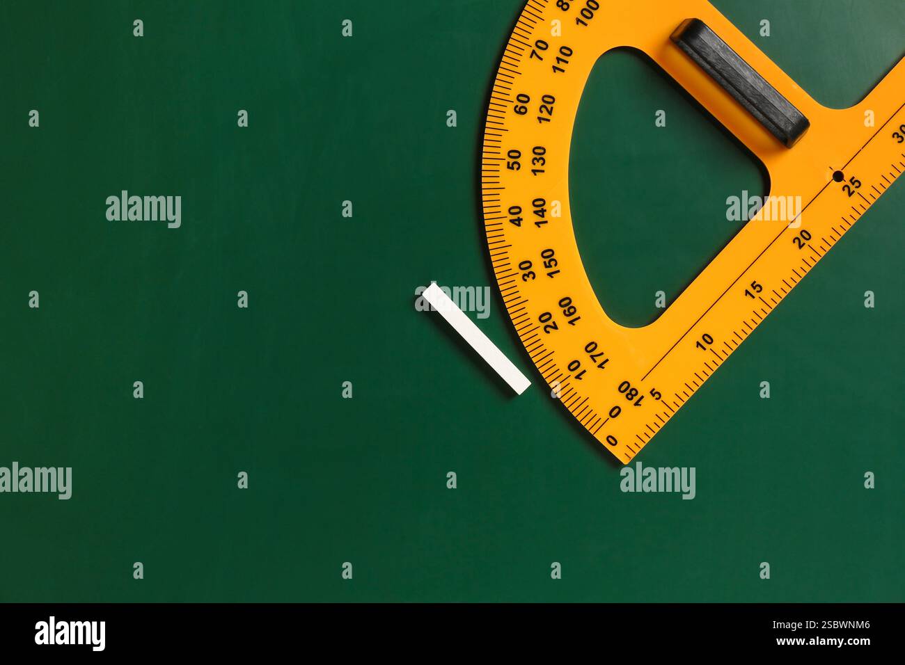 Protractor ruler and chalk on green chalkboard, top view. Space for ...
