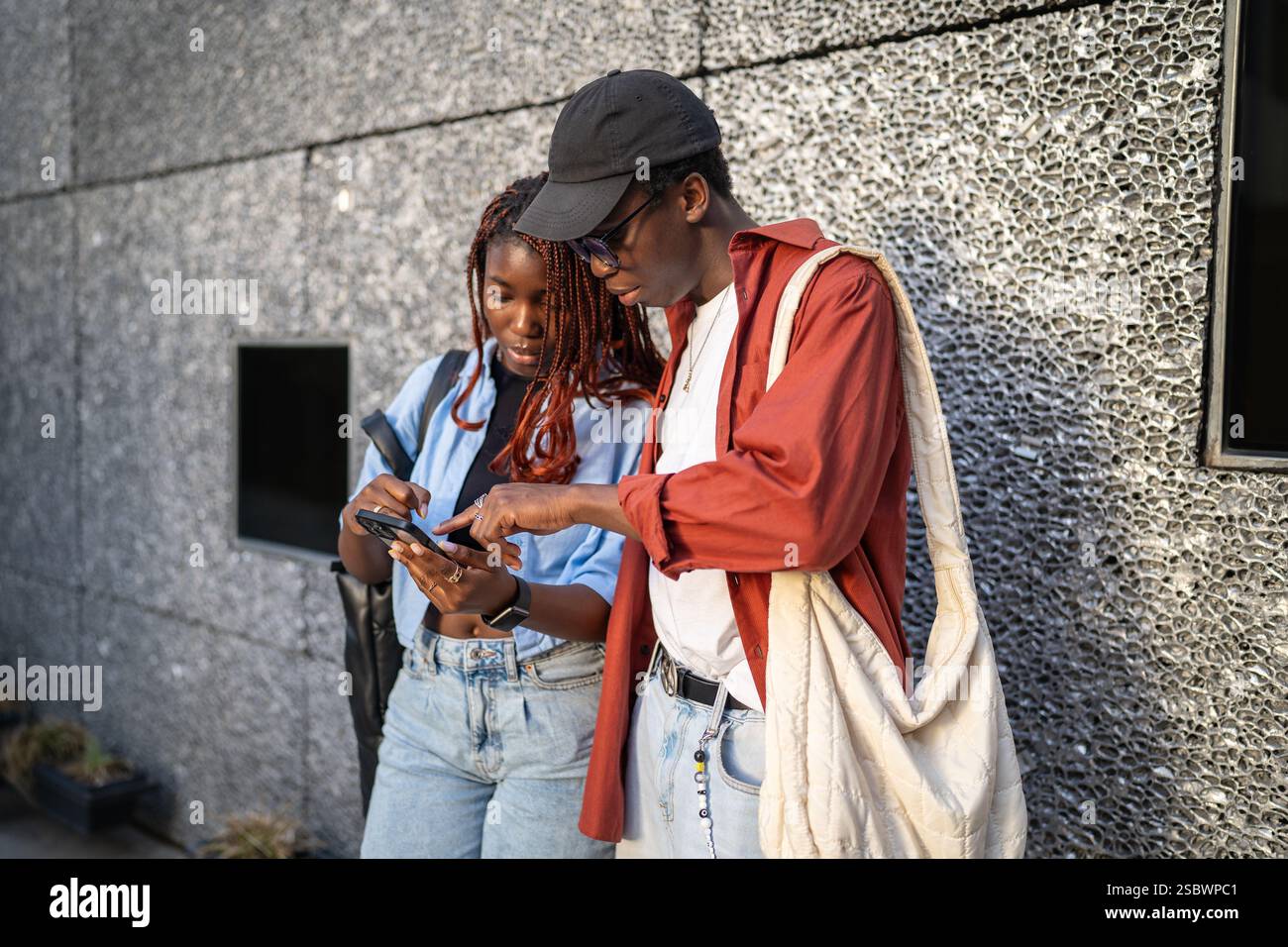 Stylish Black couple check phone for directions on city walk. Man ...
