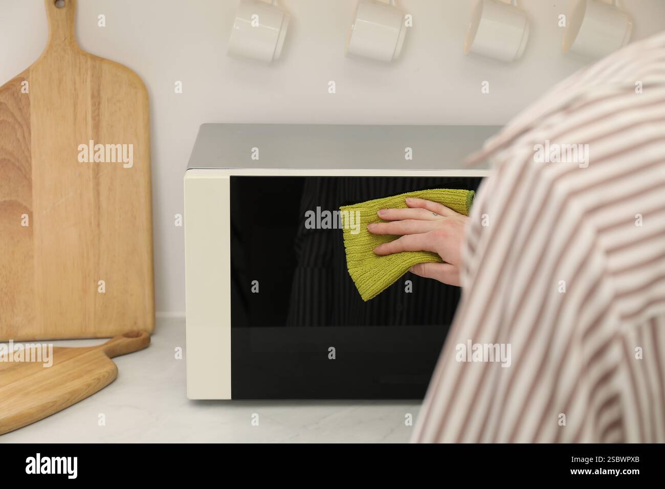 Woman cleaning microwave oven with rug in kitchen, closeup Stock Photo ...