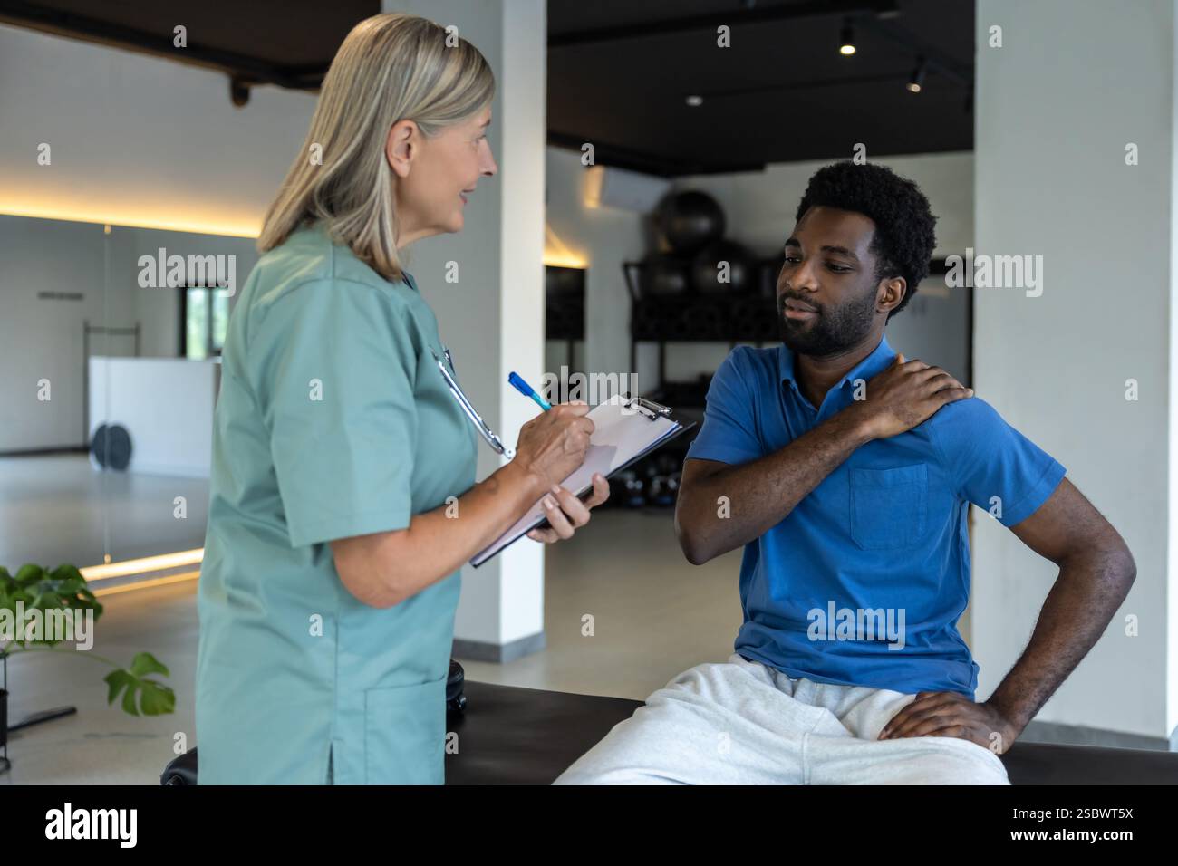 Female physical therapist talking to male patient and making notes ...