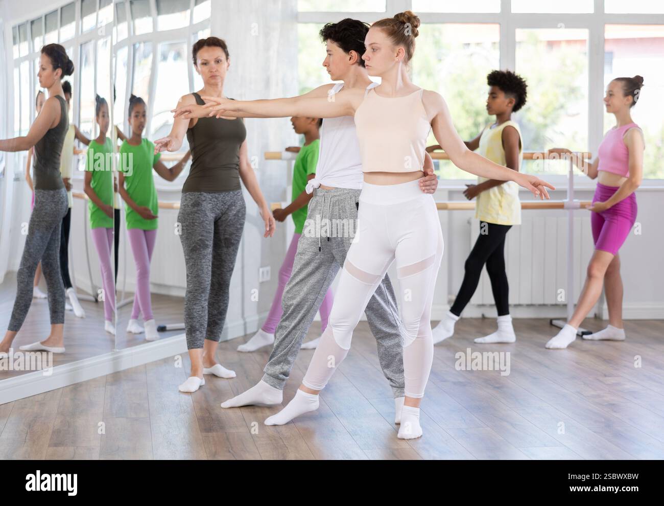 Teenage girl practicing ballet positions in pair with boy in dance ...