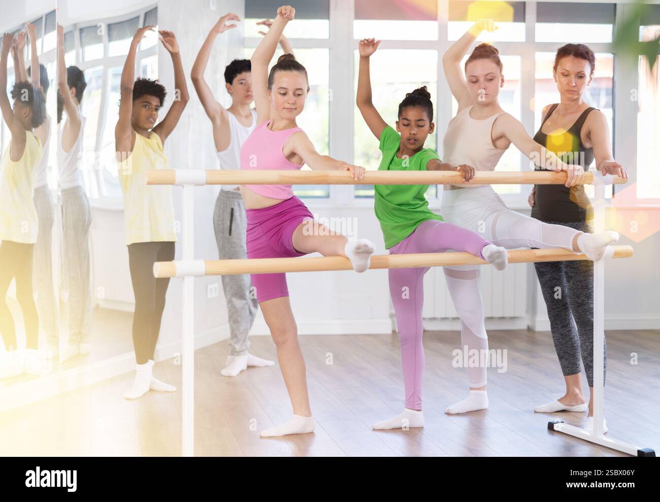 Teen girls performing ballet stretches at barre in dance studio Stock ...