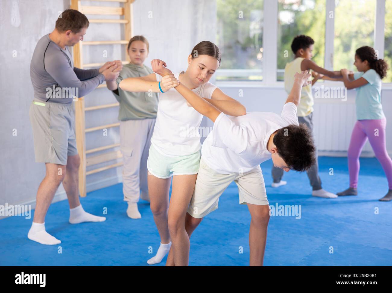 Tween girl practicing painful armlock in training bout with boy during ...