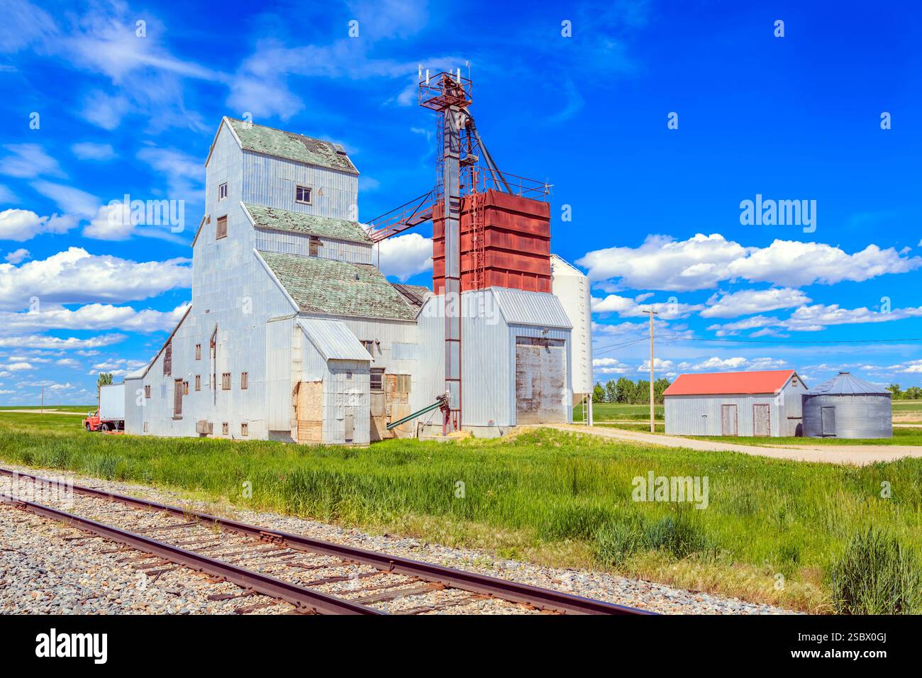 Grain silo is in the middle of a field. The silo is surrounded by a ...