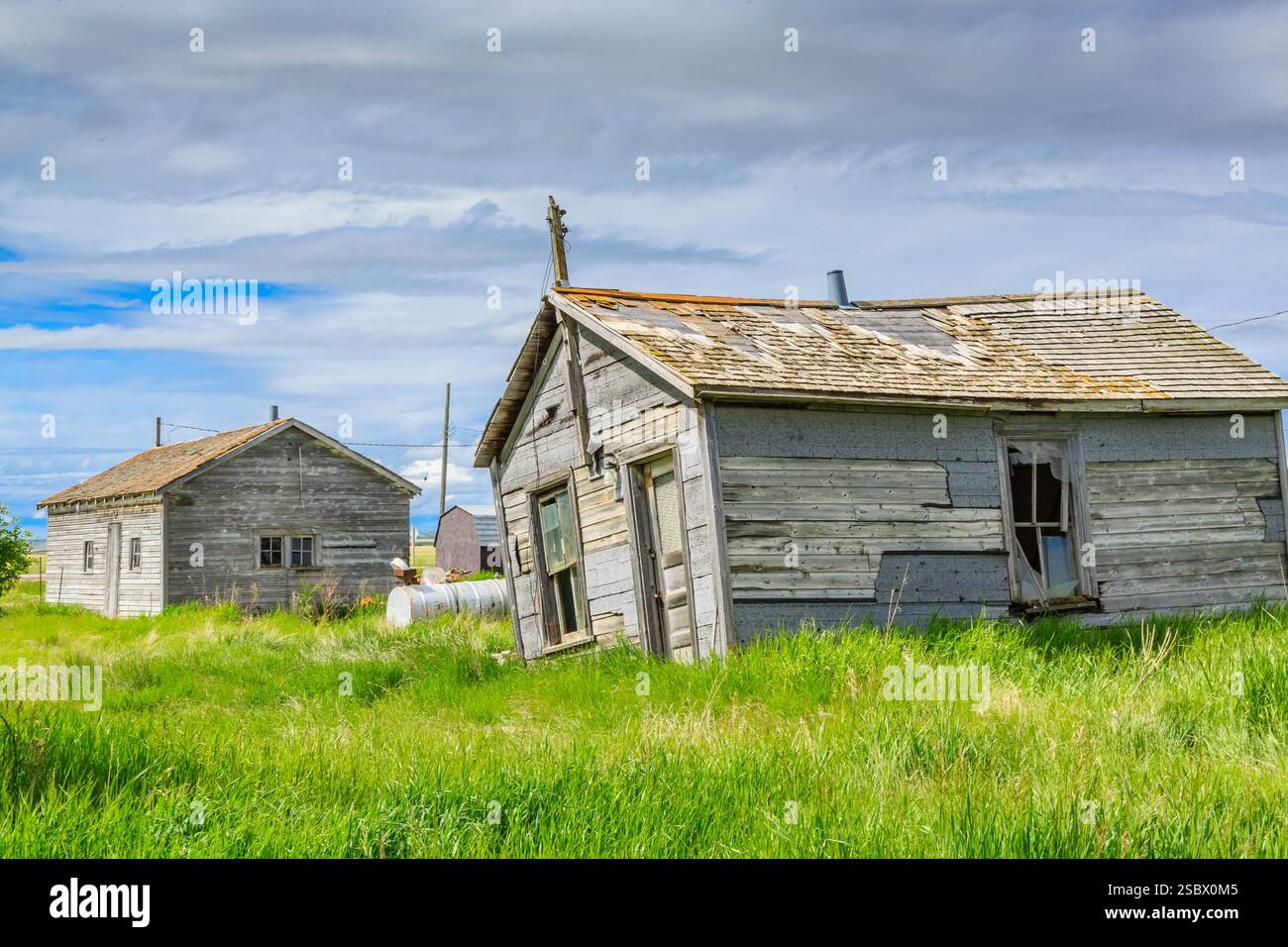 Small house with a crooked roof sits in a field. The house is ...
