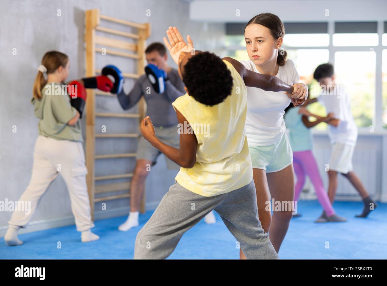 Girls and boys practicing in pair self defence movements with male ...
