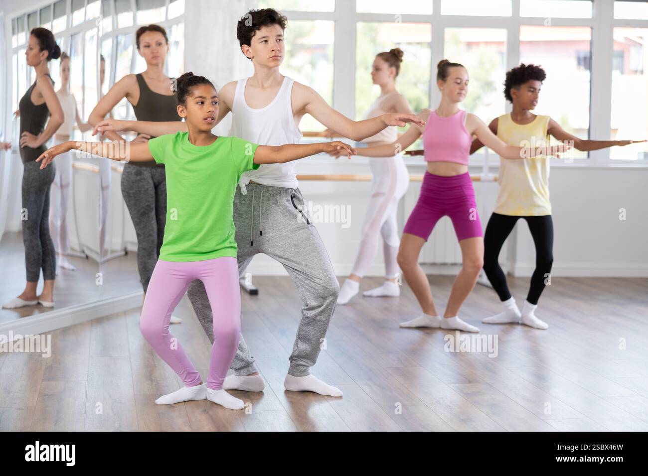 Teenage girl and boy practicing plie position of ballet in dance studio ...