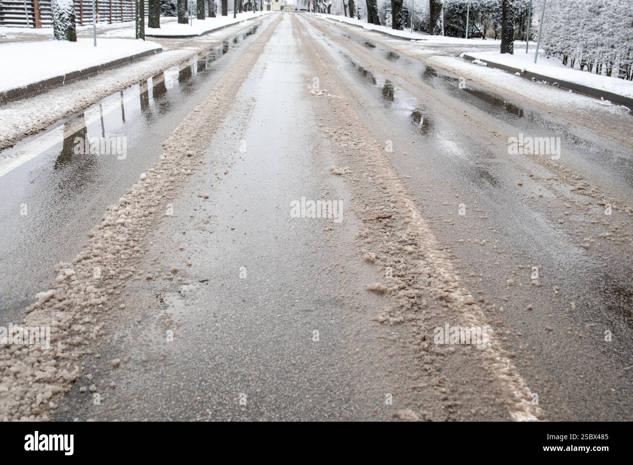 Road after snowfall, melting snow treated with salt. Winter season ...