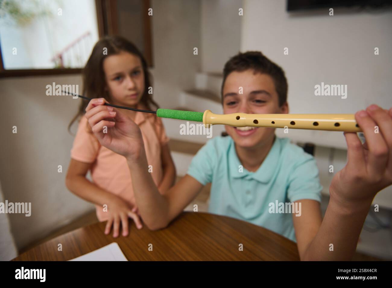 Two kids indoors examining a musical recorder, evoking curiosity about ...