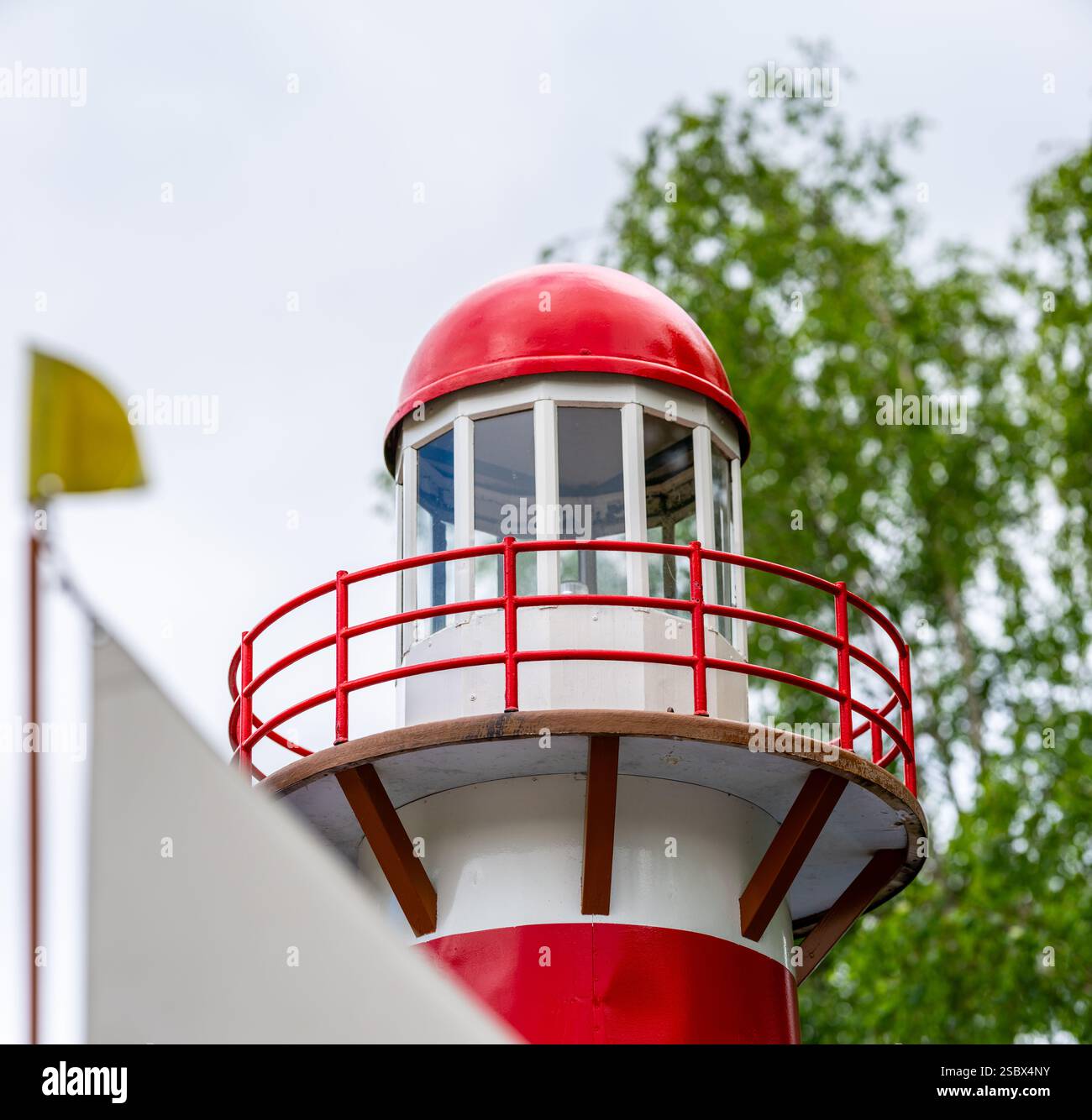 lighthouse with red dome roof and observation deck among green trees ...