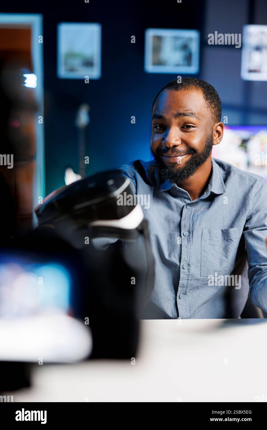 Smiling african american man presenting VR goggles to audience, filming ...