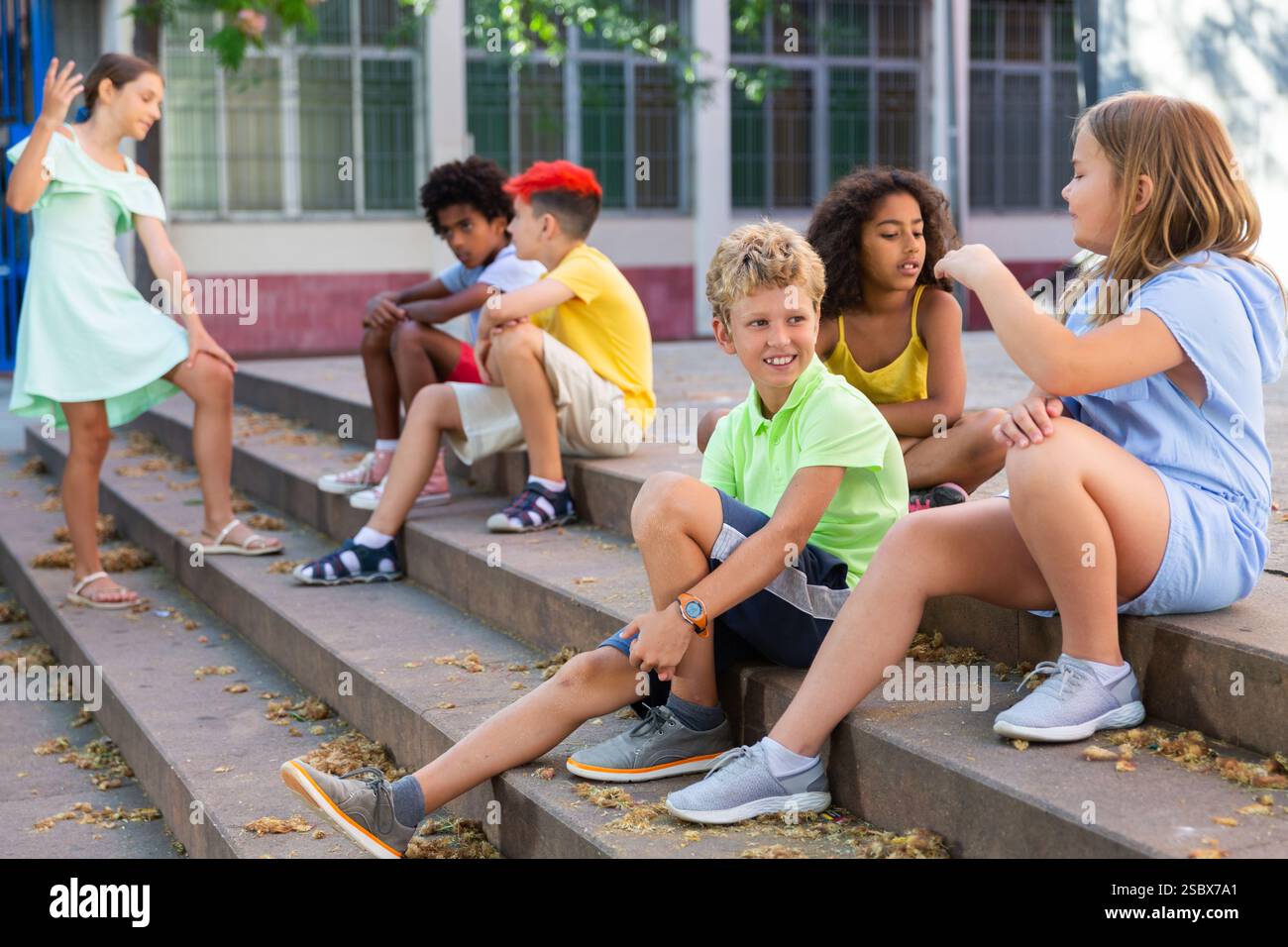 Children talking together while sitting on stairs outdoors Stock Photo ...