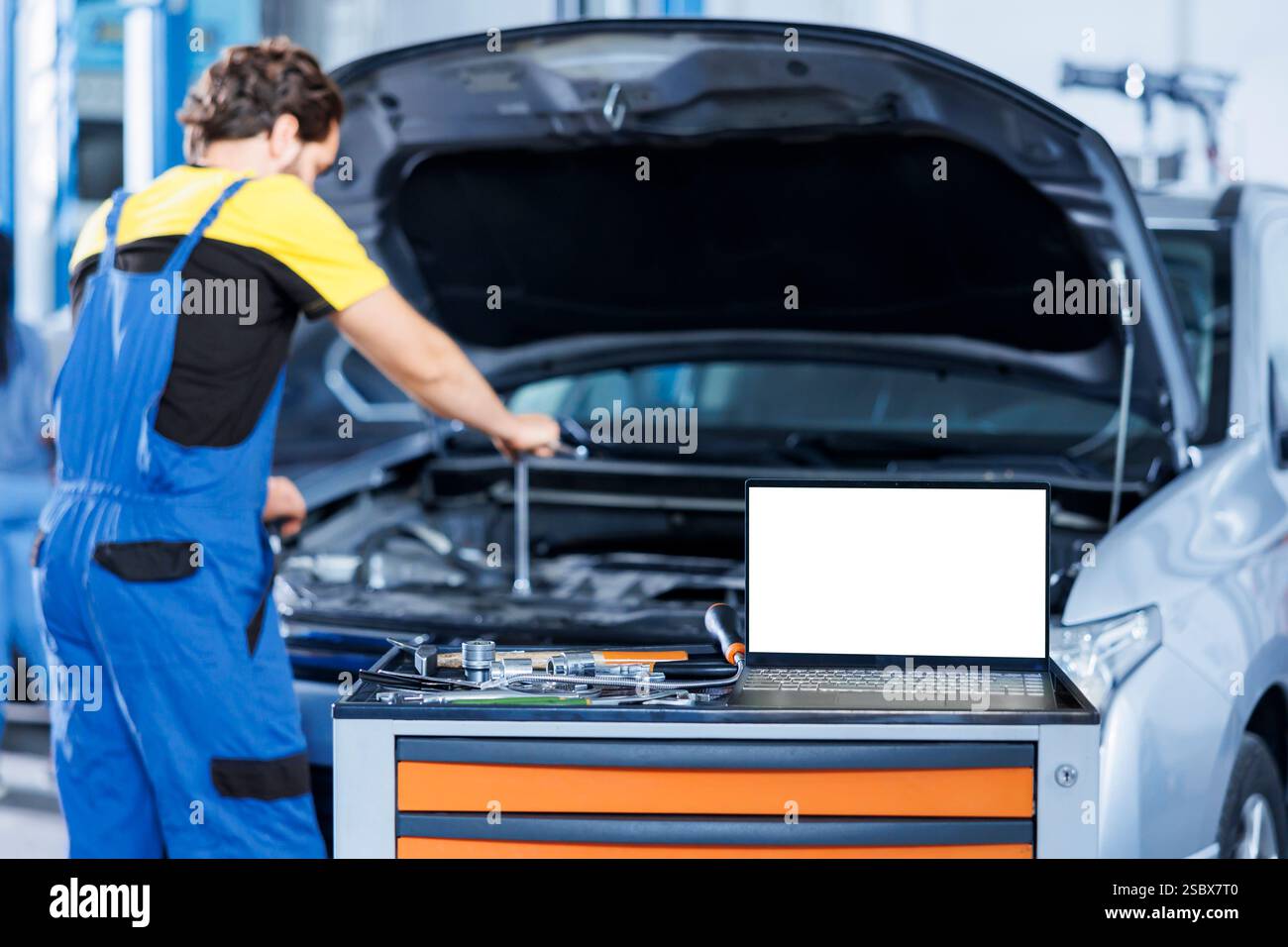Mockup laptop on car service work station bench with mechanic in ...