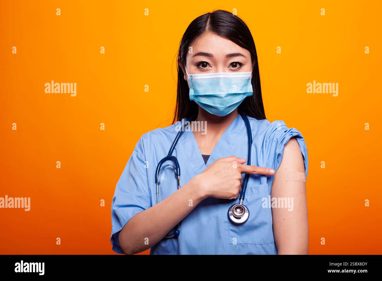 Portrait of asian woman in medical uniform, showing her vaccinated arm ...