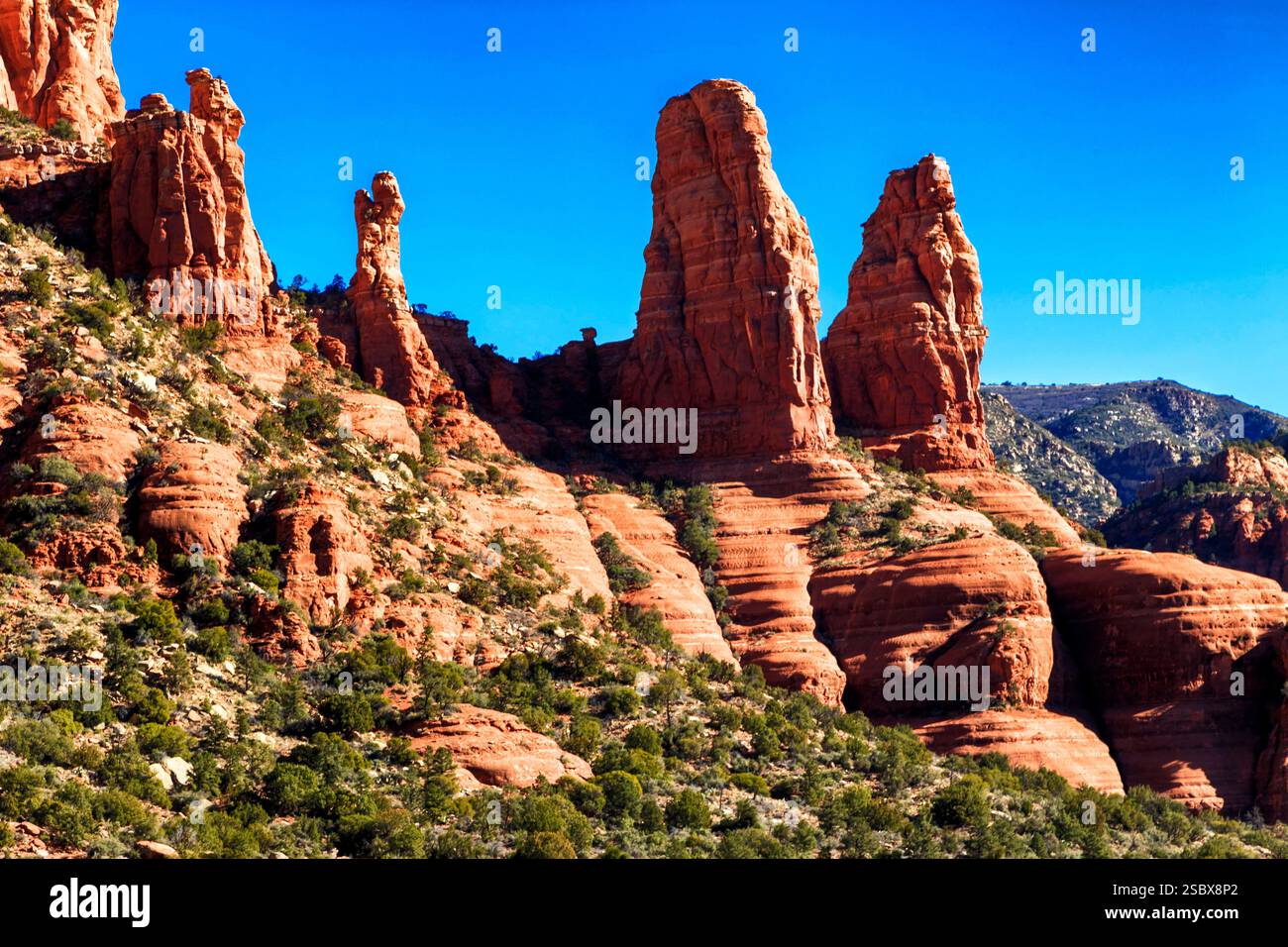 A mountain range with a red rock formation. The rocks are tall and have ...