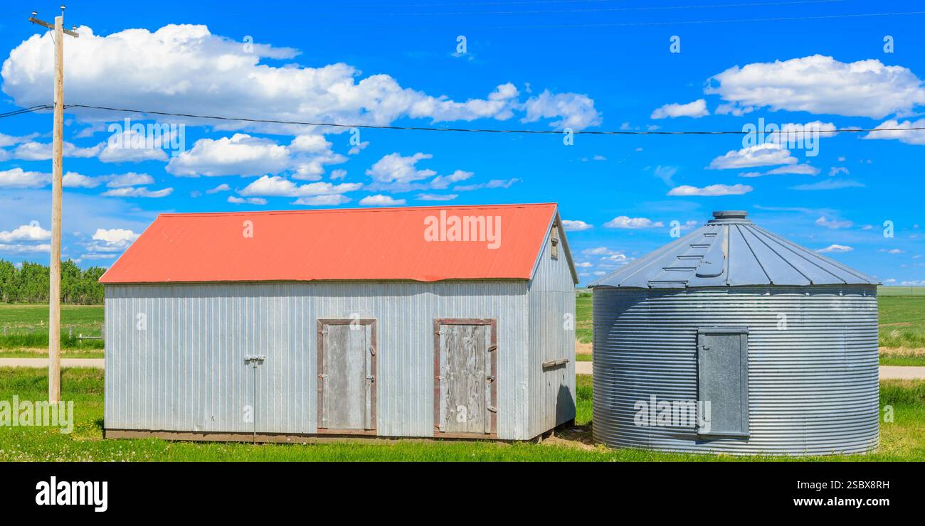 Red barn with a metal roof sits next to a large metal tank. The barn is ...
