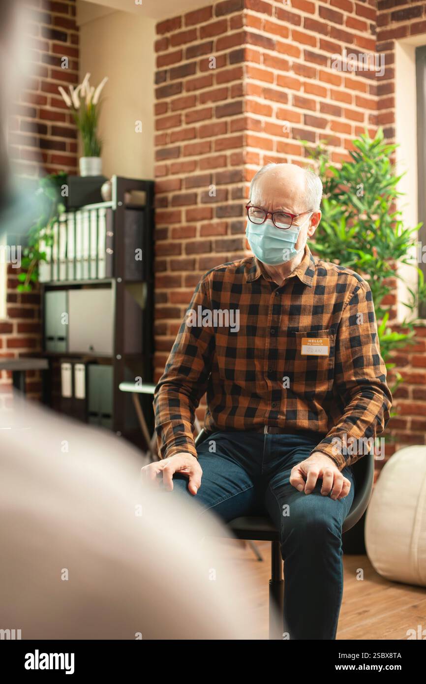 Portrait of senior man seated in brick wall office, attending mental ...