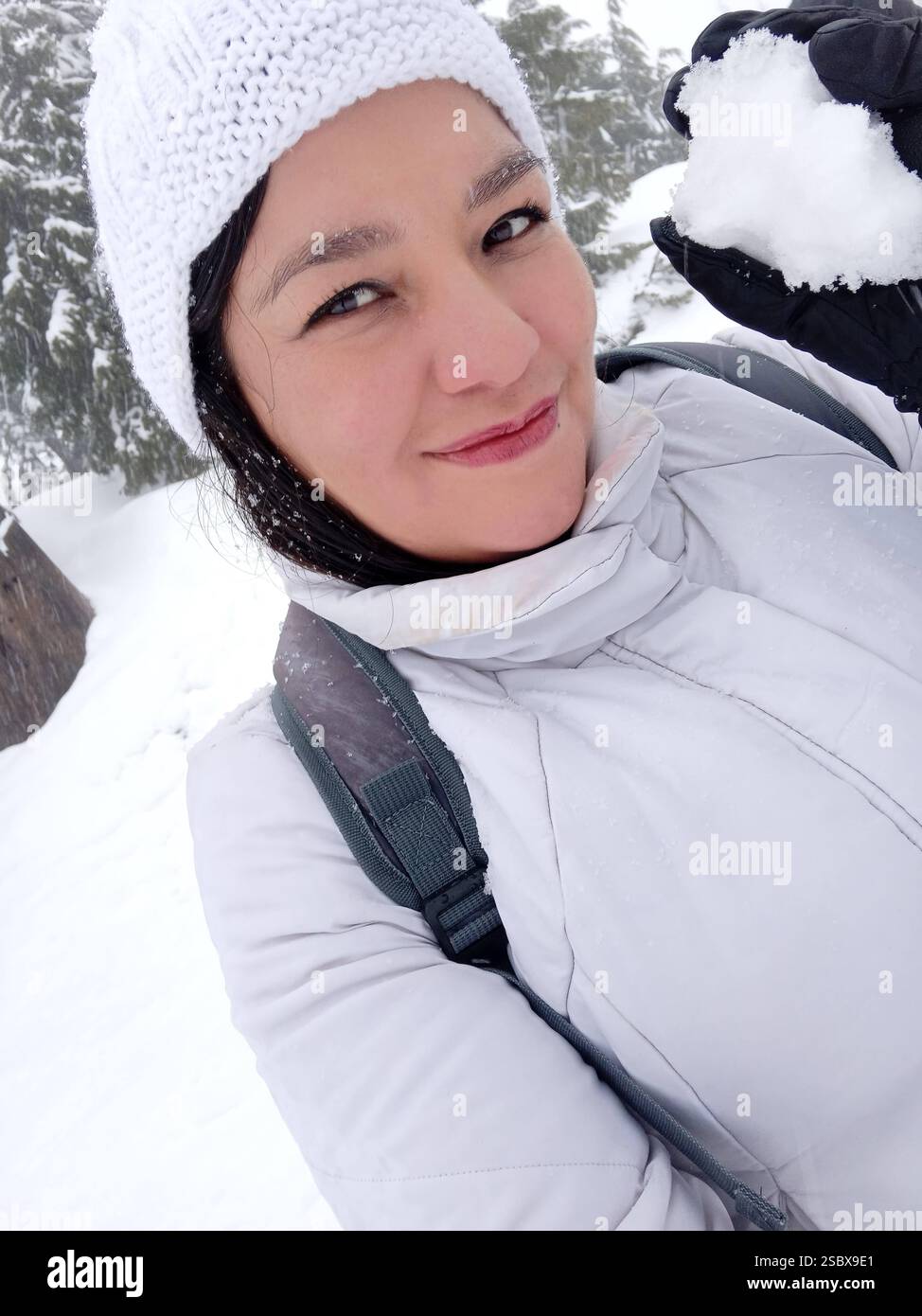 Latin adult woman plays throwing snowballs in the snow due to a cold ...