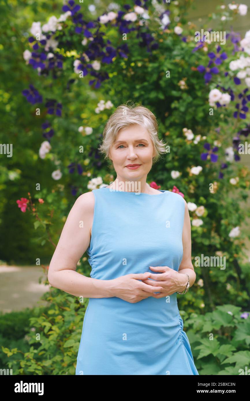 Outdoor portrait of beautiful middle age woman in her 50s, wearing blue ...