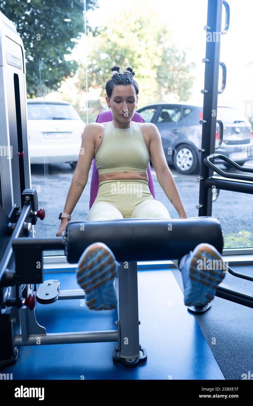 Focused female athlete performing lower body exercise on weight machine ...