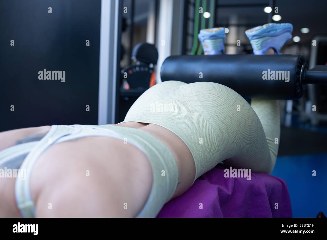 Woman working out her legs on exercise equipment in a gym, concentrating on building strength ...