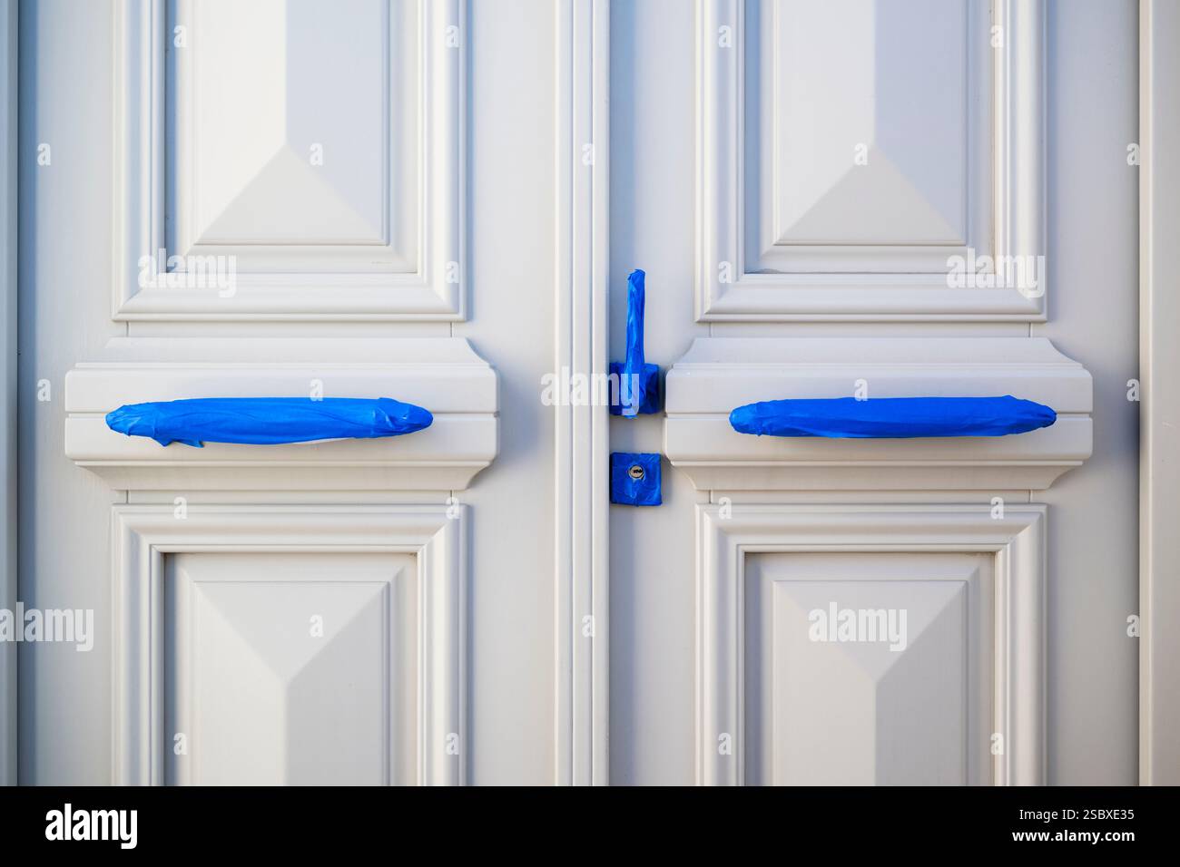 White decorated wooden door with door handles and lock wrapped in blue ...