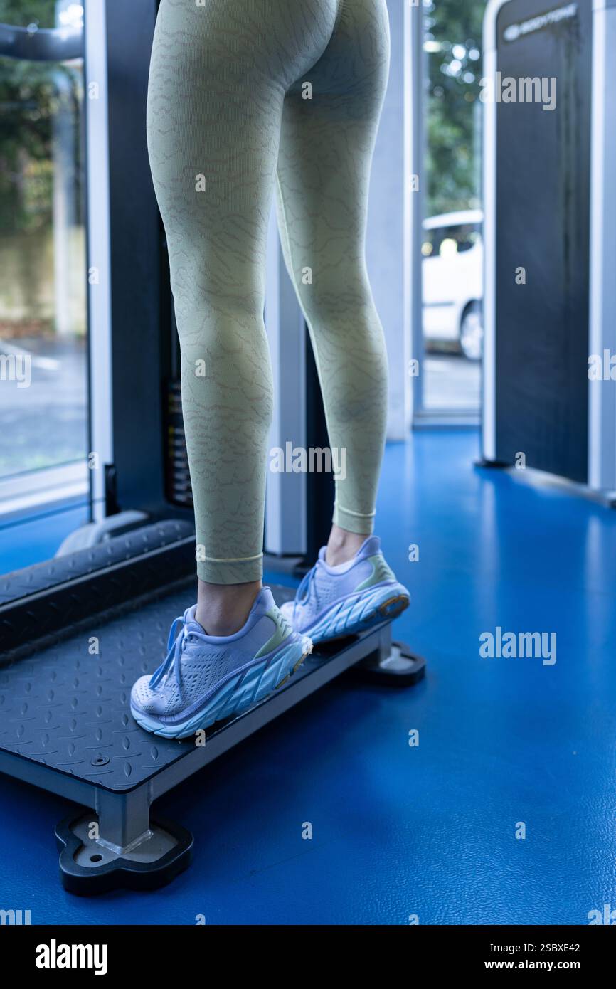 Close up of female legs performing standing calf raises on a step ...