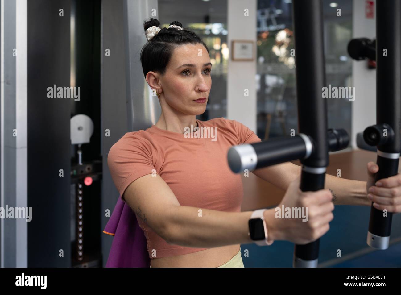 Determined sportswoman performing a chest fly exercise on a pec deck ...